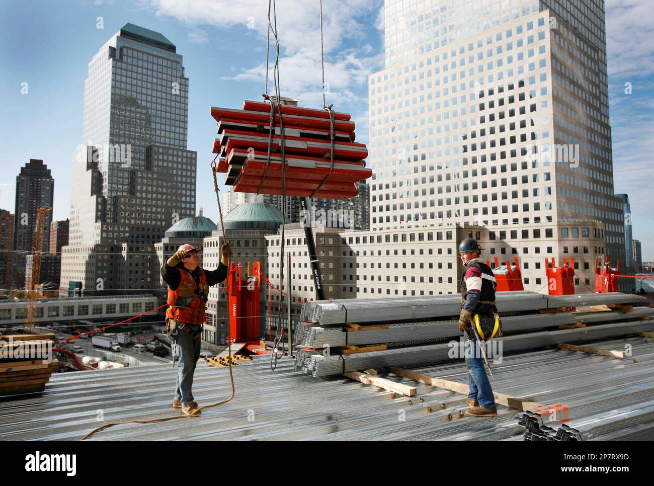 Ironworkers guide a load of steel to the fourth floor deck of One World ...