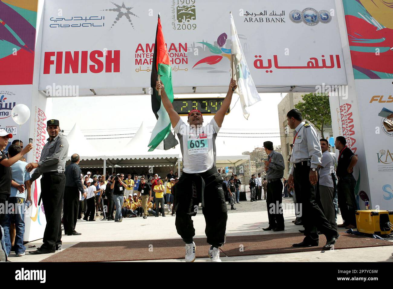 A Jordanian participant raise a national flag as he reaches the finish ...