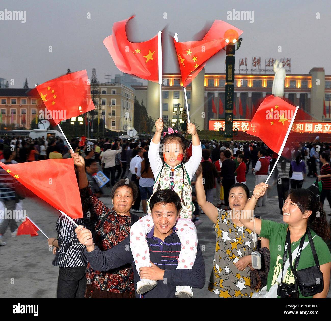 Local residents wave flags after a flag raising ceremony celebrating ...