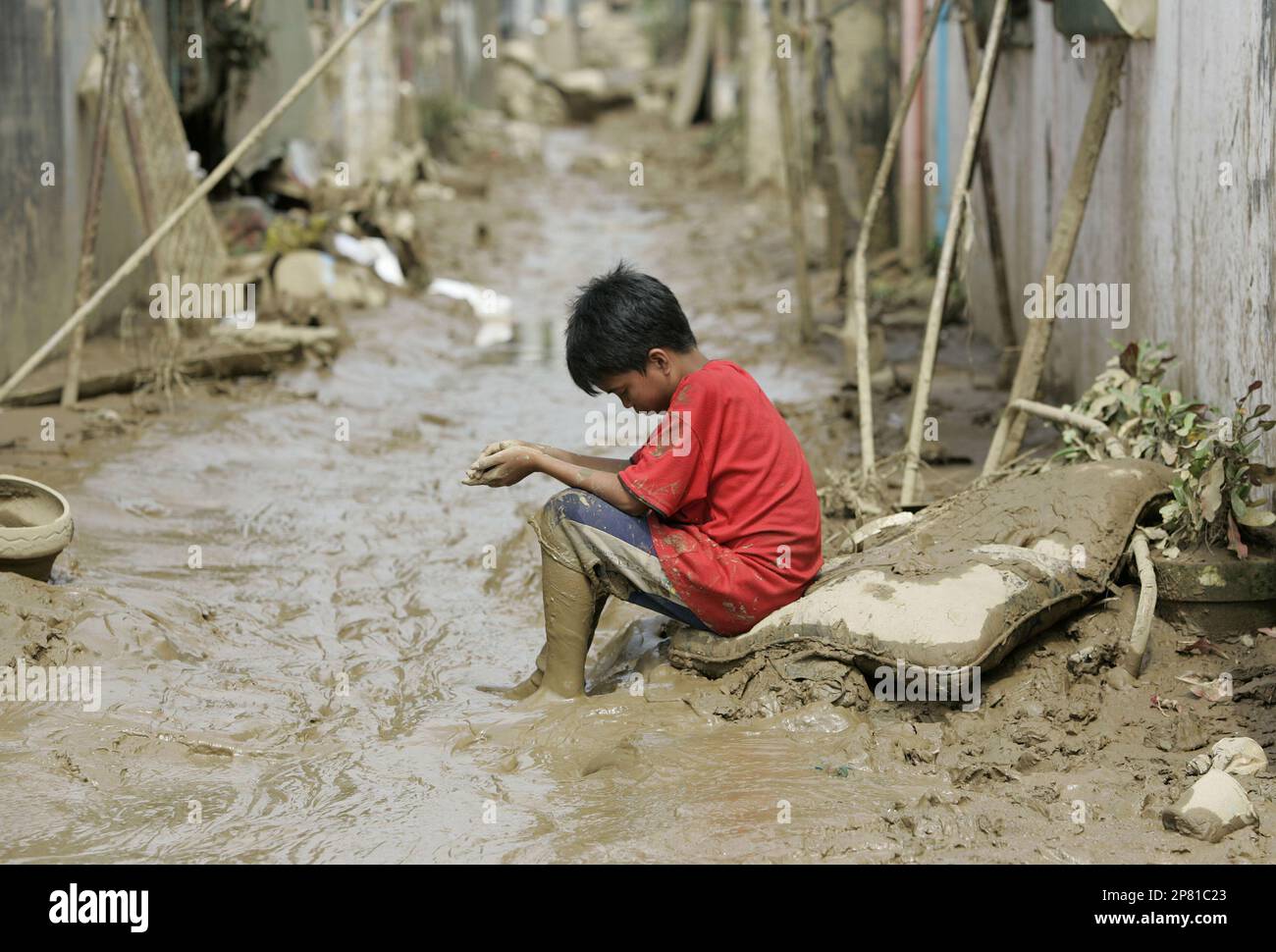 A Filipino boy rests along a muddy street in Rodriguez, Rizal province ...