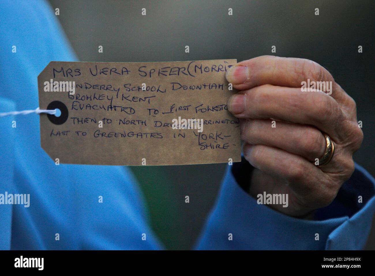 A former evacuee, shows a handwritten label with information about her ...