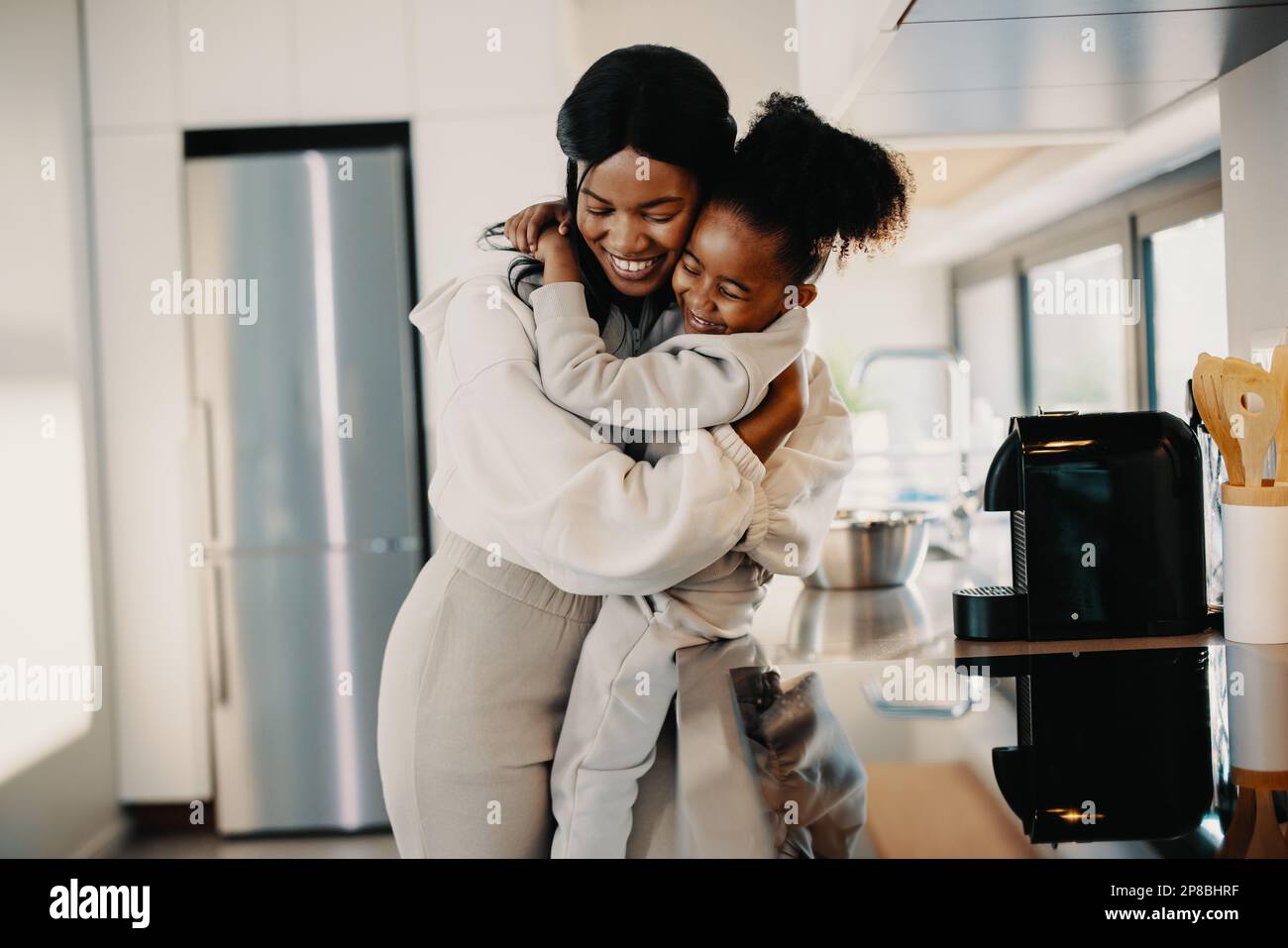 Je t'aime maman, petite fille câle sa mère dans la cuisine. La mère et ...
