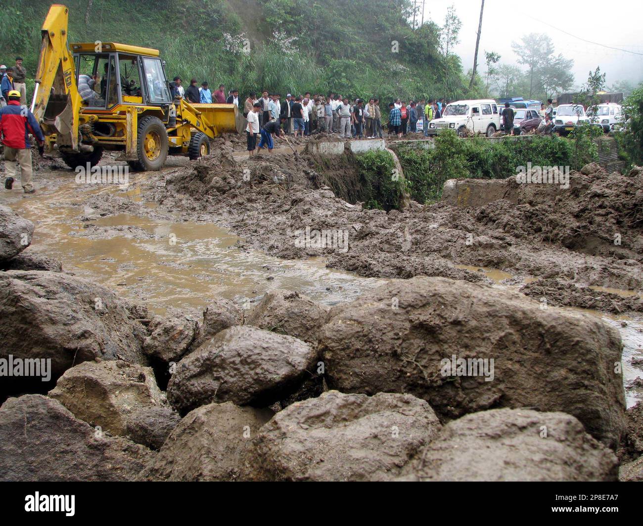 Civic workers remove mud after a mudslide from a hill track as stranded tourists wait on ...