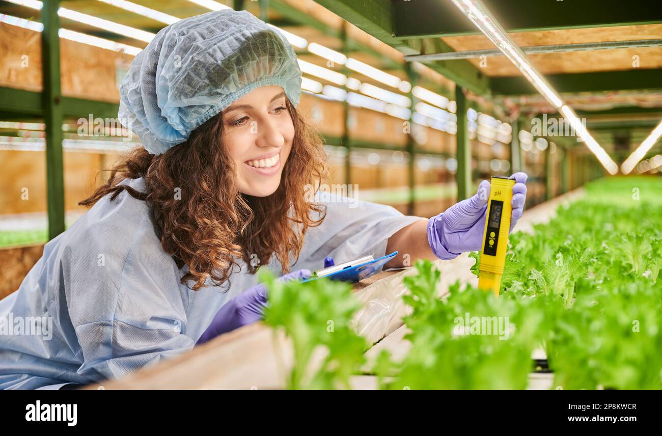Jardinière féminine joyeuse dans un capuchon jetable tenant le presse ...