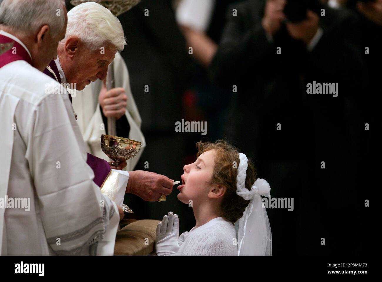 Pope Benedict XVI, second left, gives the first communion to a child ...