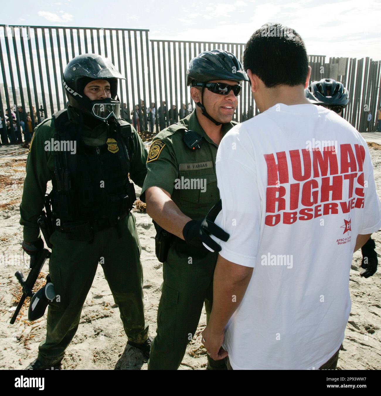U.S. Border Patrol agents block the path of protestor Pedro Rios, right ...