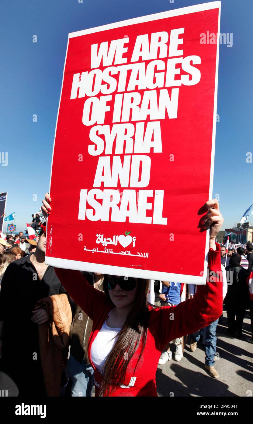 A Lebanese woman holds a banner as she attends a rally near the grave ...