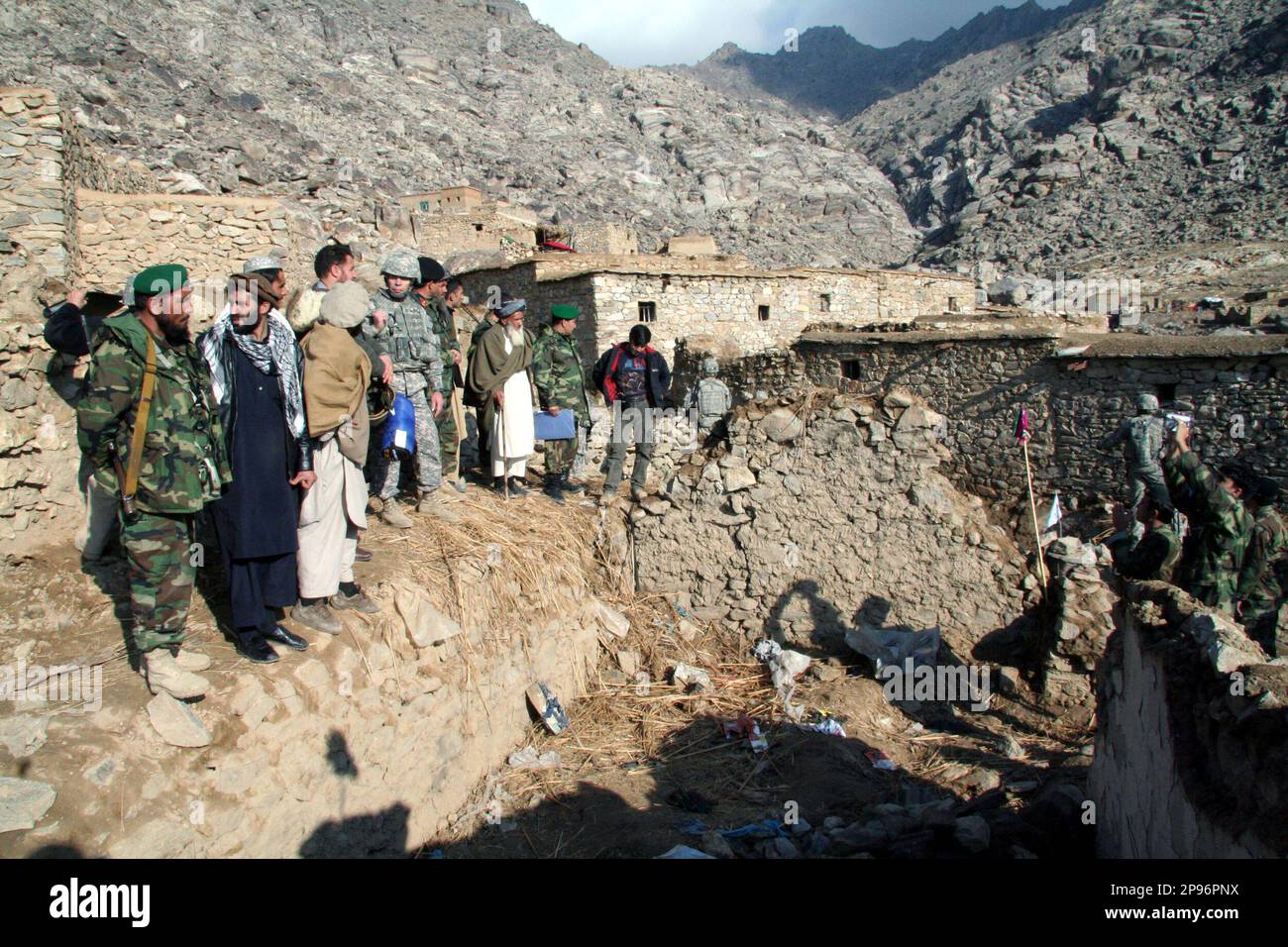 Afghan villagers and U.S. soldiers are seen around a house which was ...