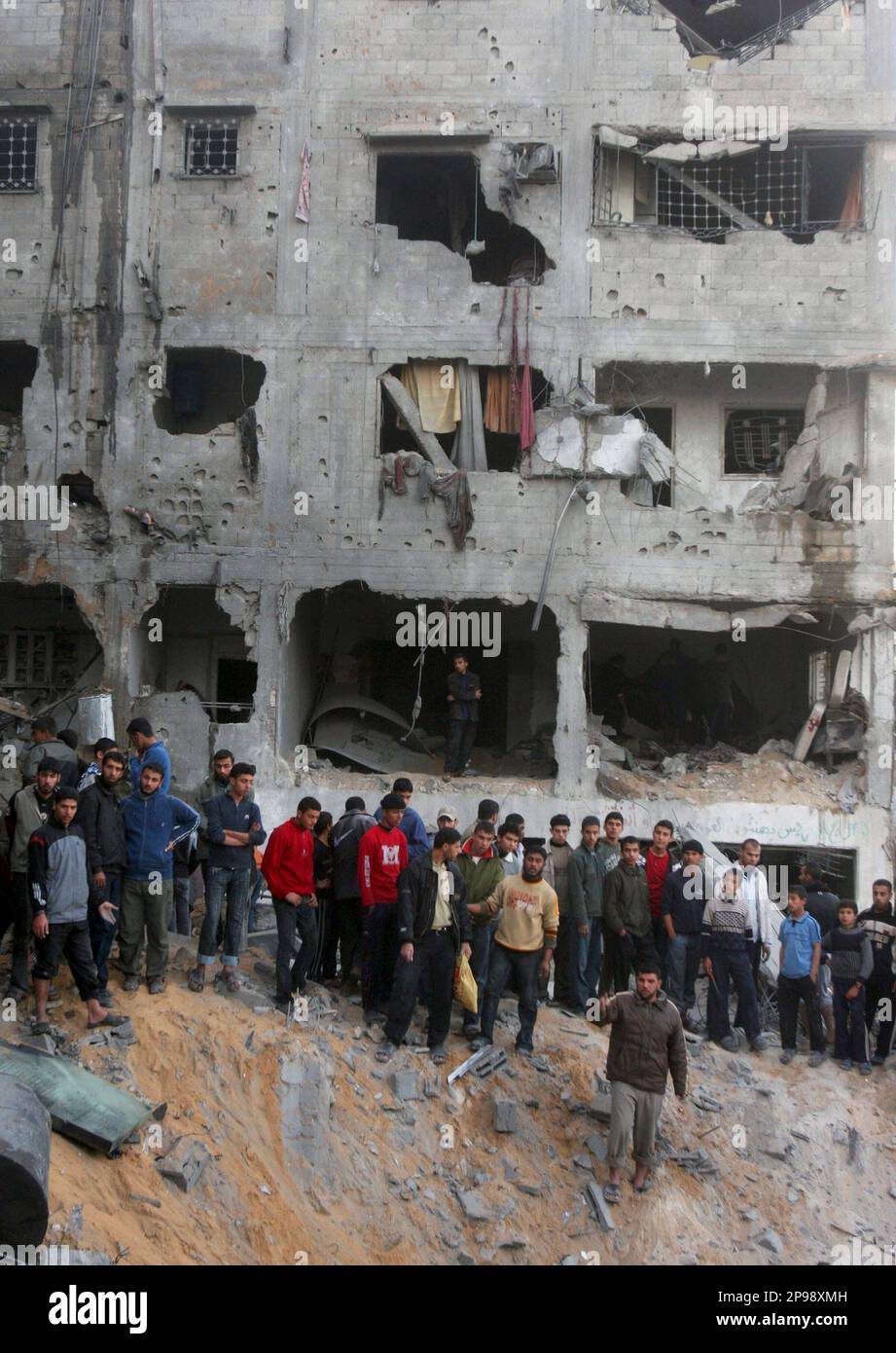 Palestinians look at the crater caused by an Israeli strike which hit ...