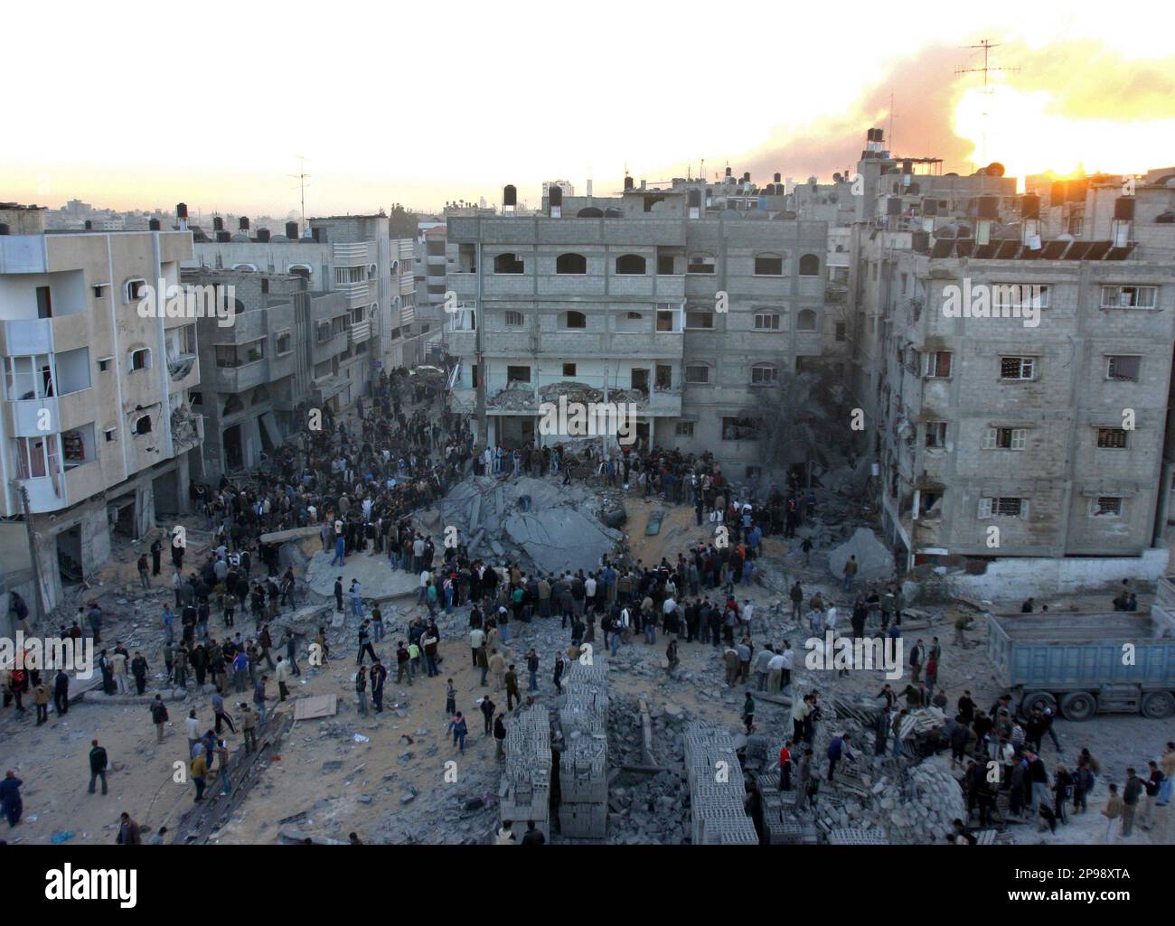 Palestinians gather around the crater caused by an Israeli strike which ...