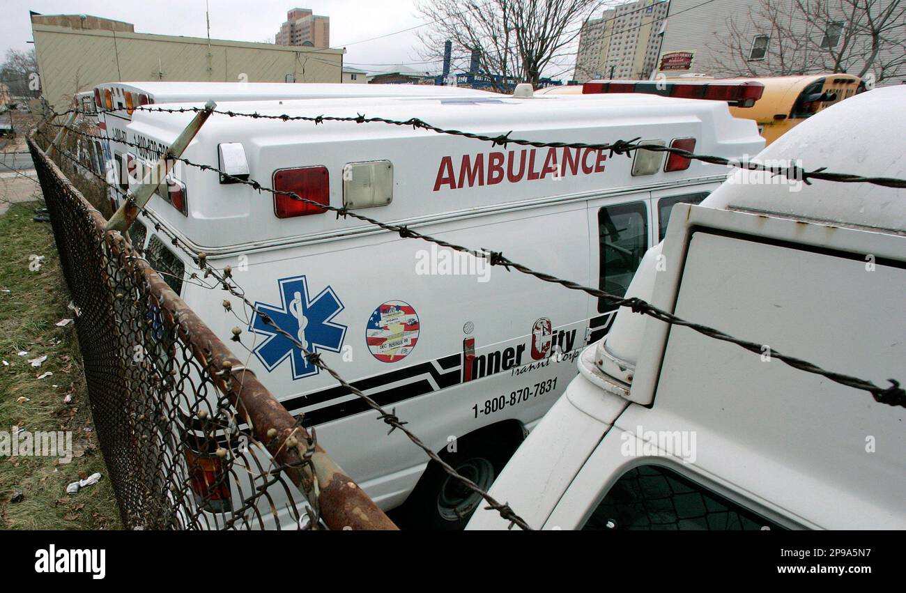 A storage lot with ambulances surrounded by fence topped with barbed ...