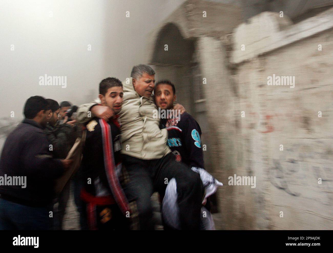 Palestinians carry a wounded man after an Israeli missile strike hit ...