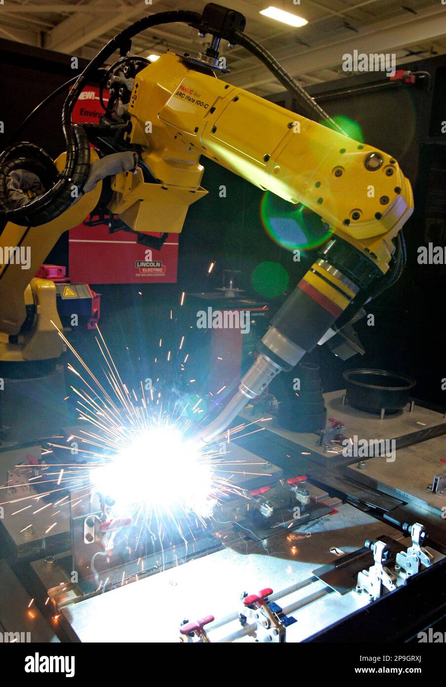 A robotic rapid arc welder welds two pieces of metal during a ...