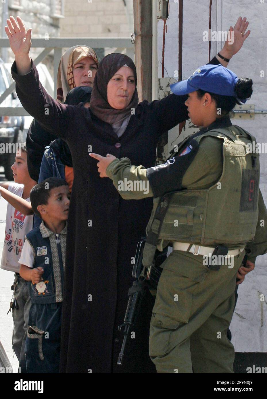 An Israeli soldier searches a Palestinian woman outside the Patriarch ...