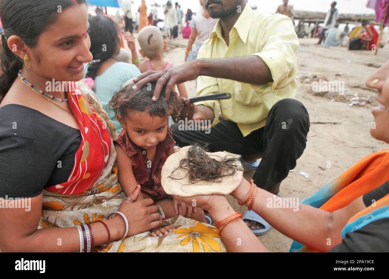A barber cuts the hair of a child, as part of a religious ritual, as ...