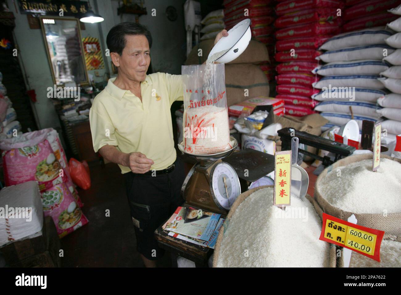 A Thai merchant weighs rice in a scale in his rice shop in Bangkok on ...