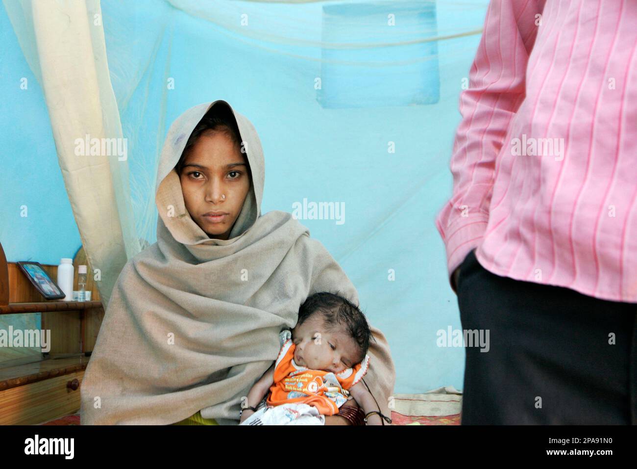 Mother Sushma holds her daughter Lali as her husband Vinod Singh stands ...