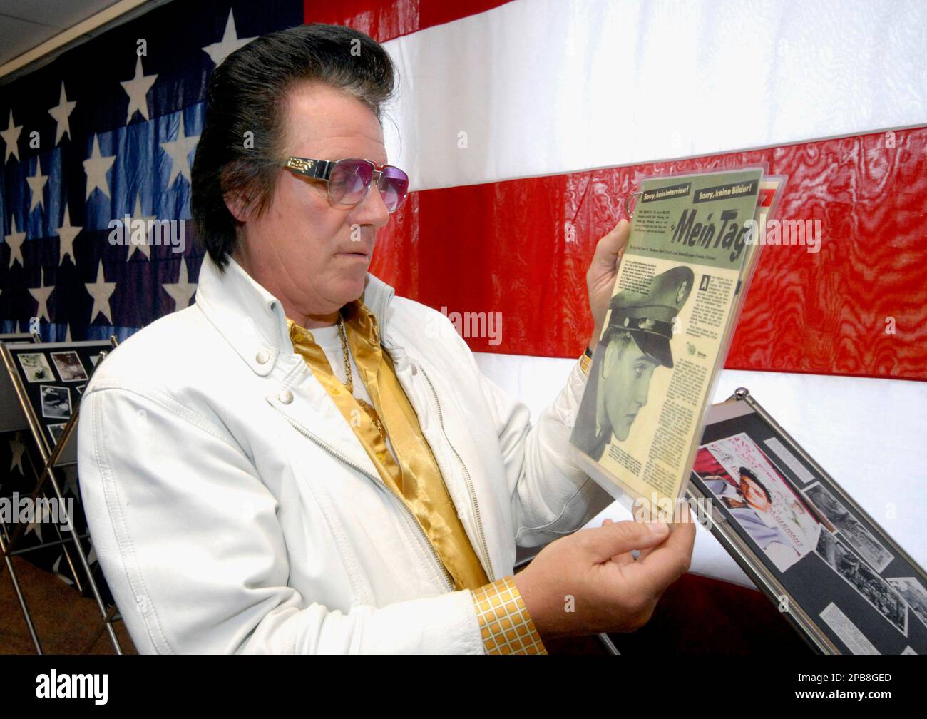An Elvis Presley impersonator looks at a historical newspaper in the US ...