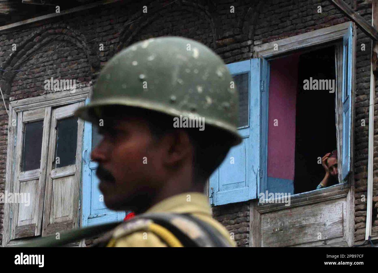 A Central Reserve Police Force soldier stands guard as a Kashmiri woman ...