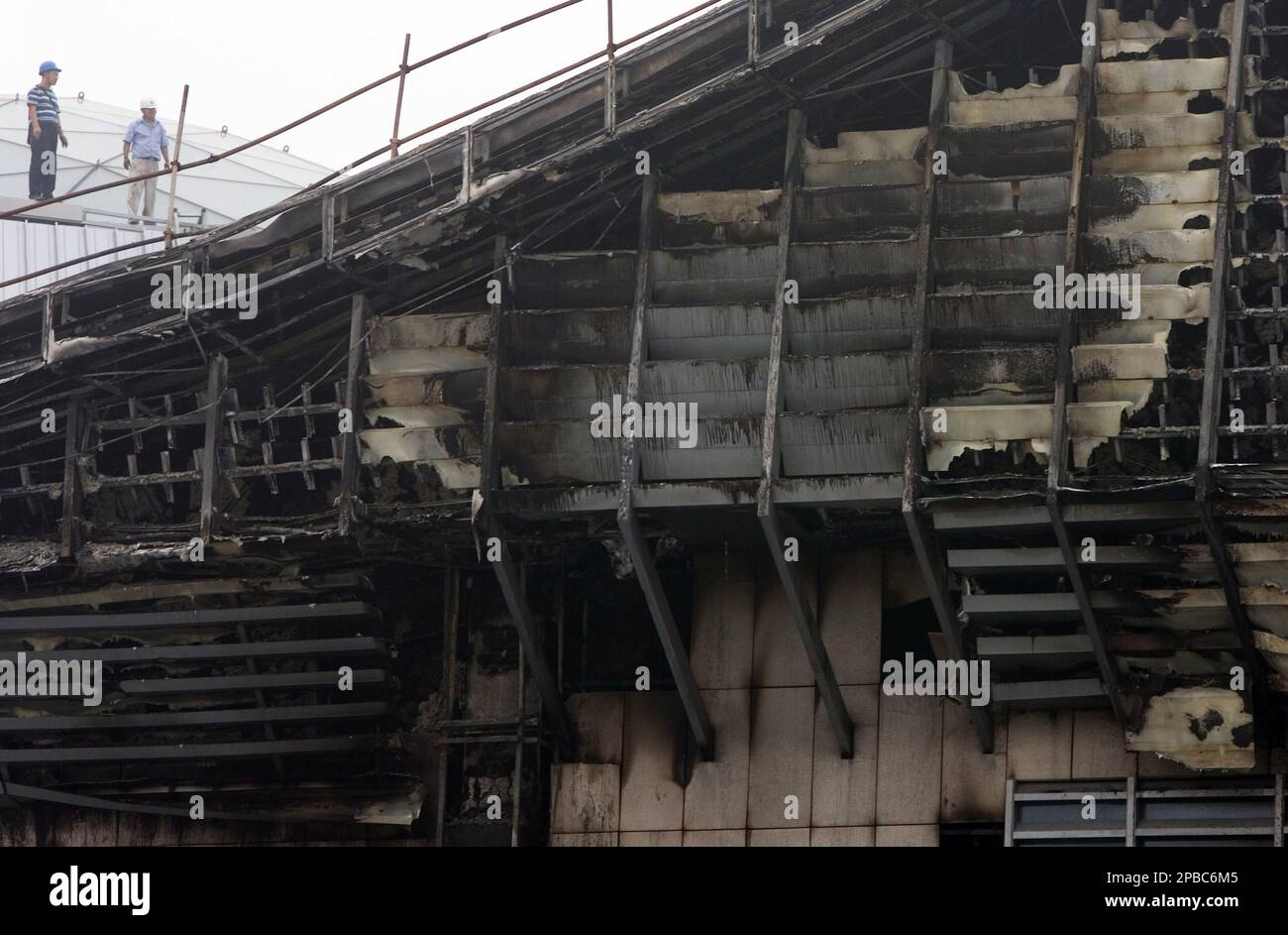 Chinese men inspect the fire damaged areas of the table tennis venue ...