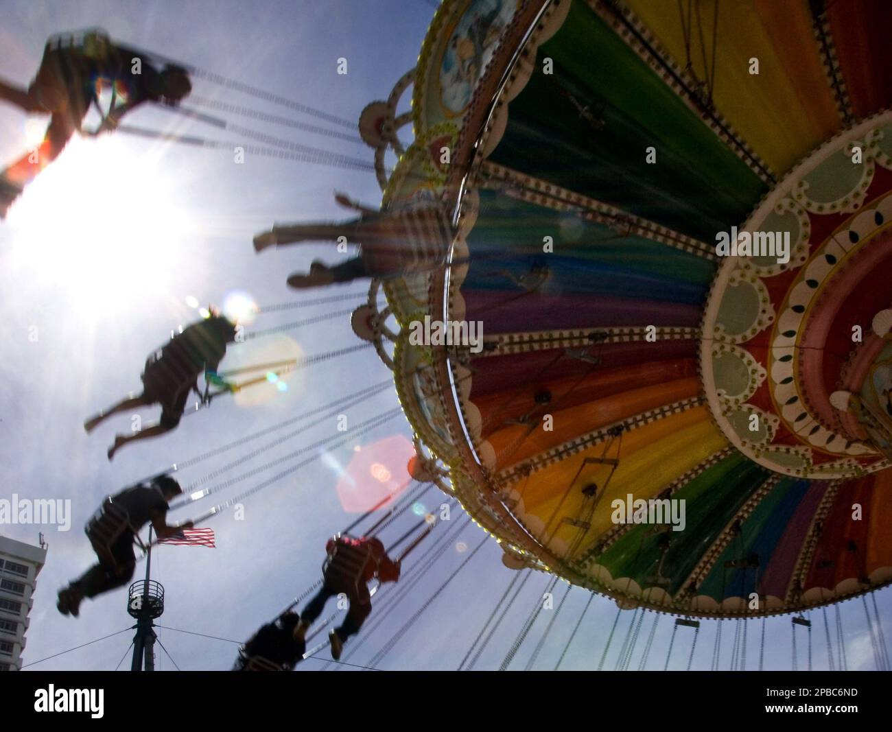Visitors playing the rodeo rider are silhouetted against the sun at the ...