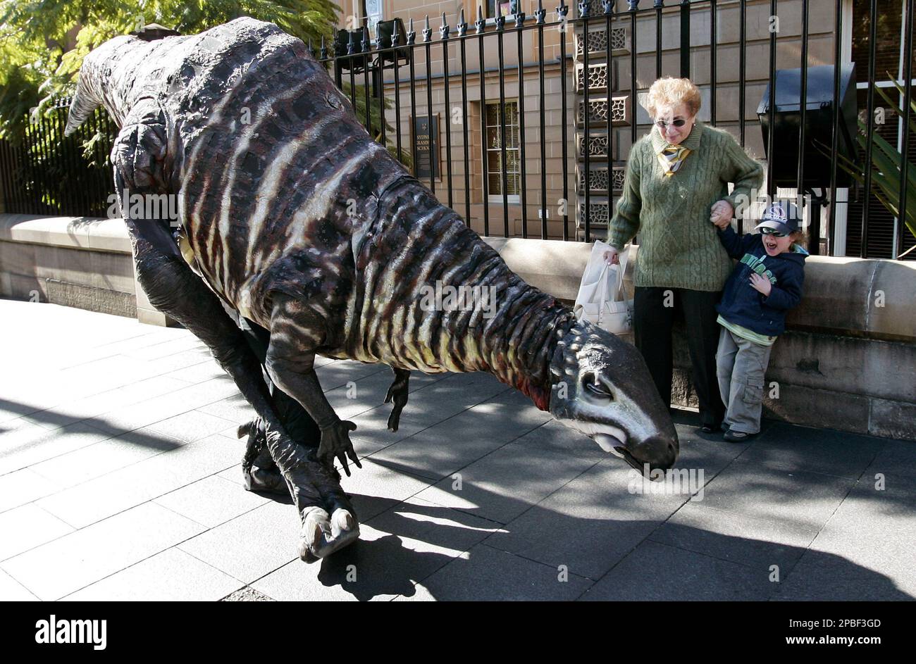 A young boy reacts as a Dryosaurus dinosaur walks past him outside the ...