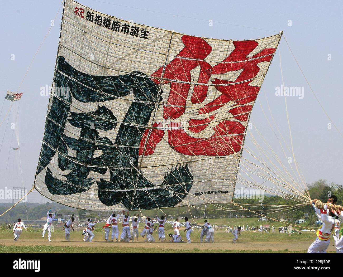 Volunteers try to pull a giant kite during the annual Sagami Big Kite ...