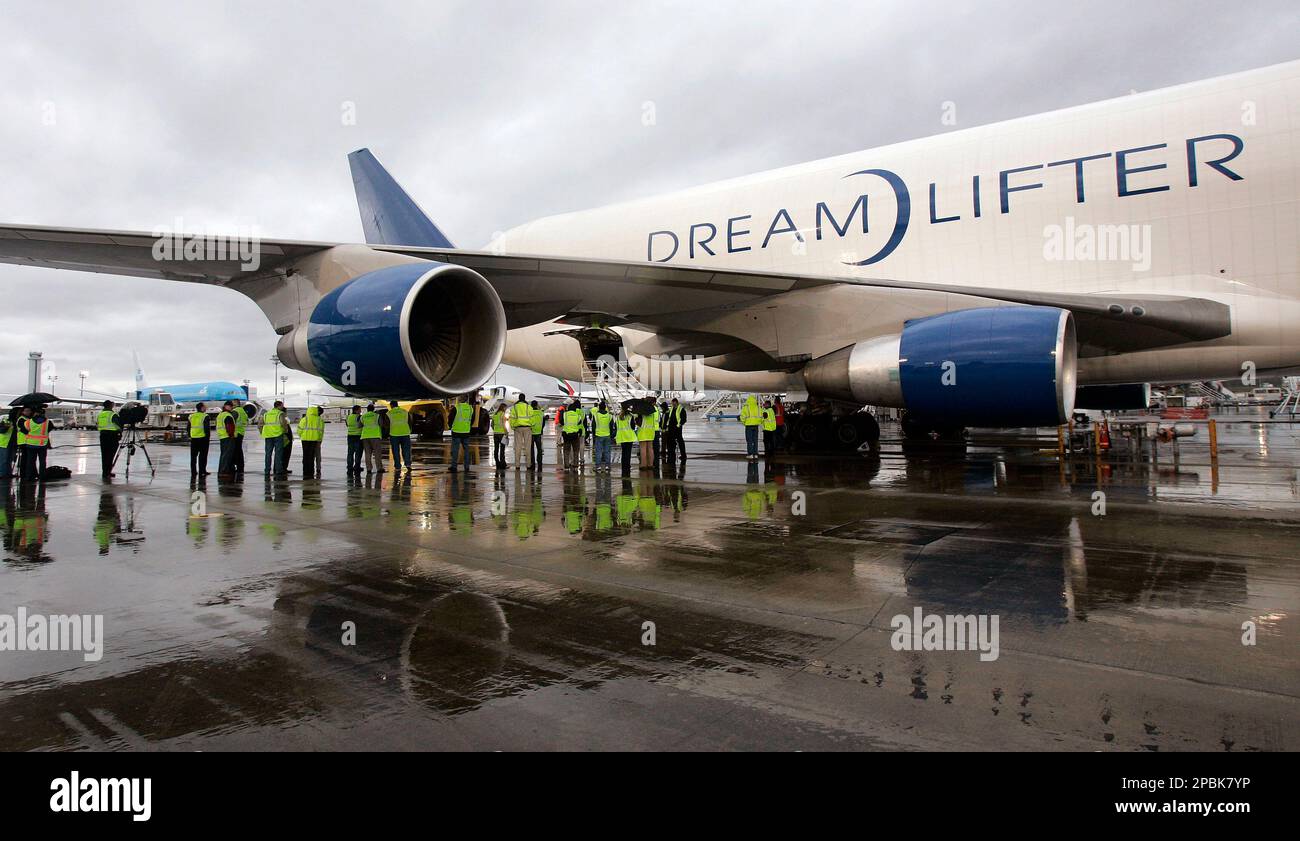 Employees line up under a wing as they wait in the rain for a Boeing ...