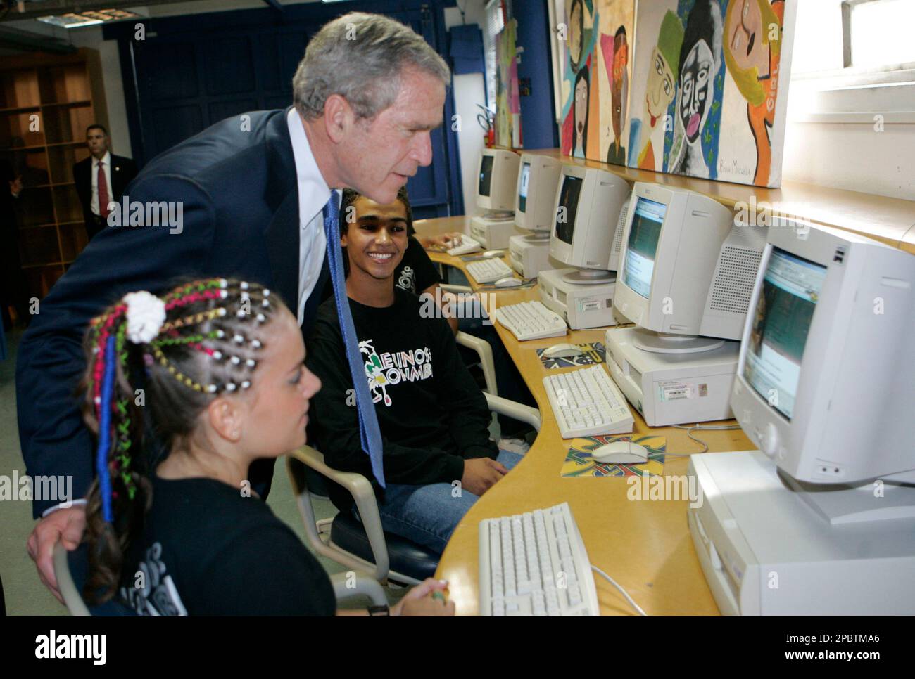 U.S. President George W. Bush leans in as he looks over examples of ...