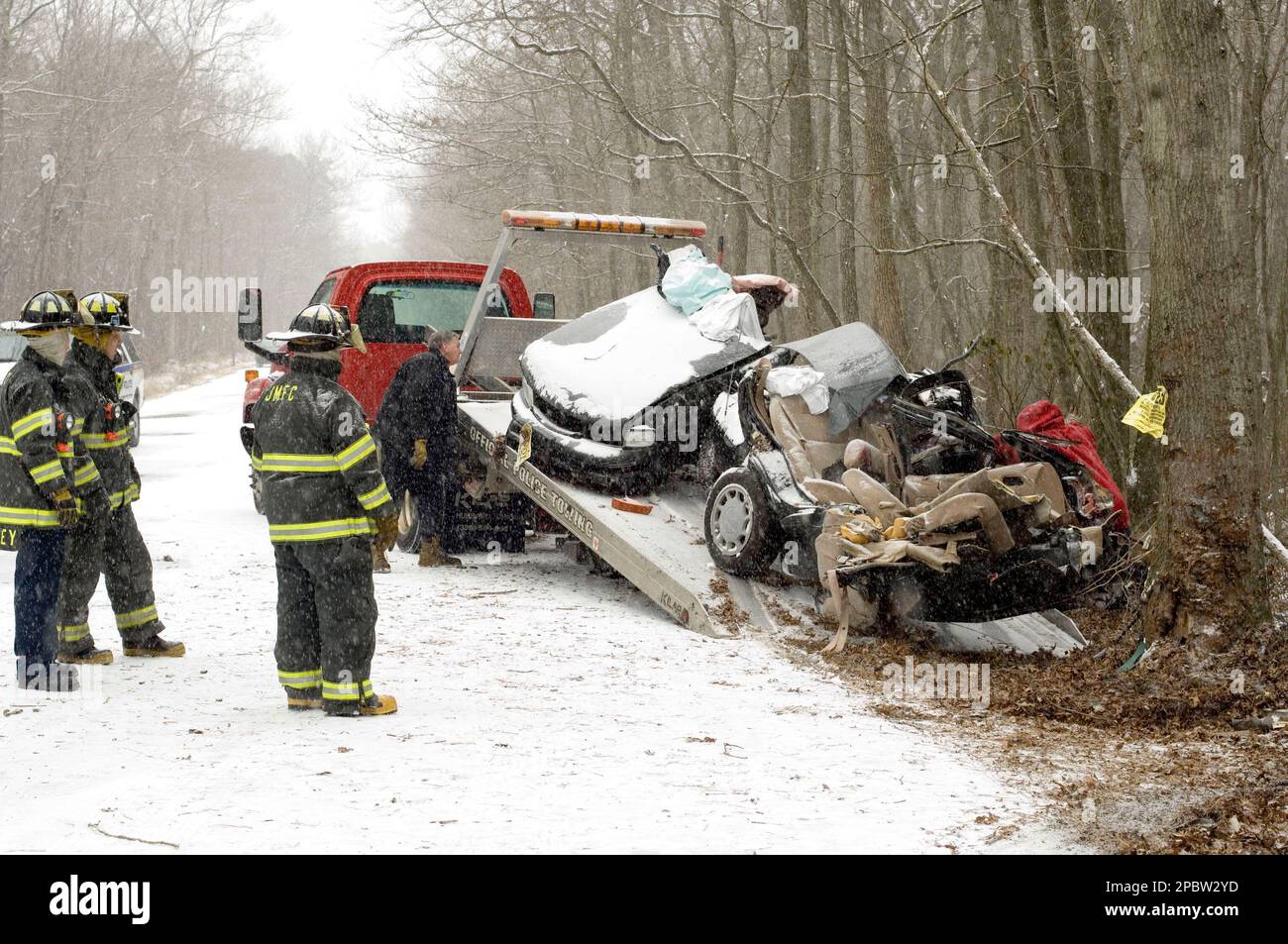Firefighters look on as the second half of a car involved in a fatal ...