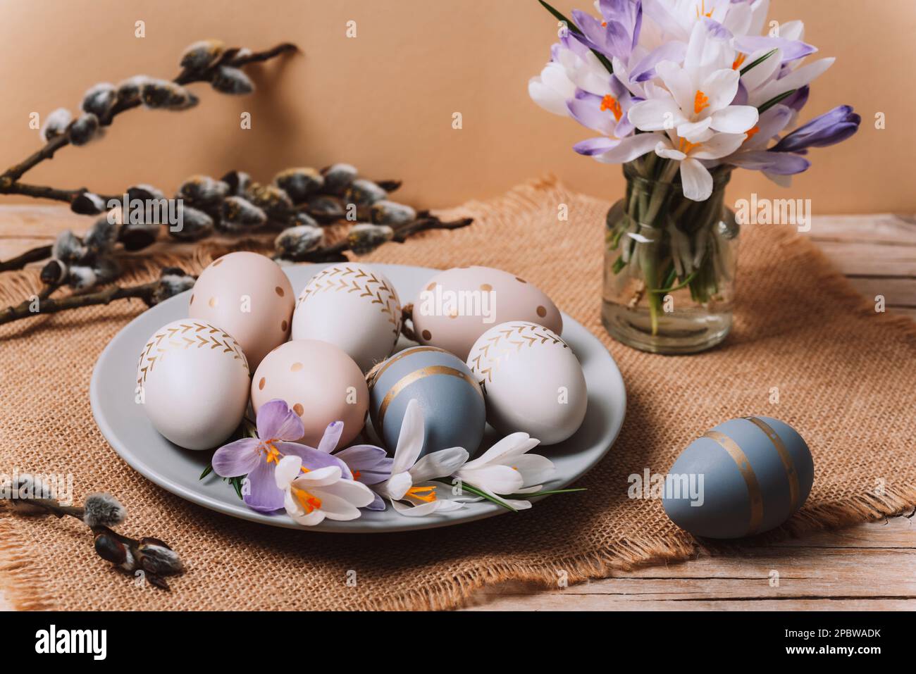 Assiette avec œufs de Pâques peints, fleurs printanières et branches de ...