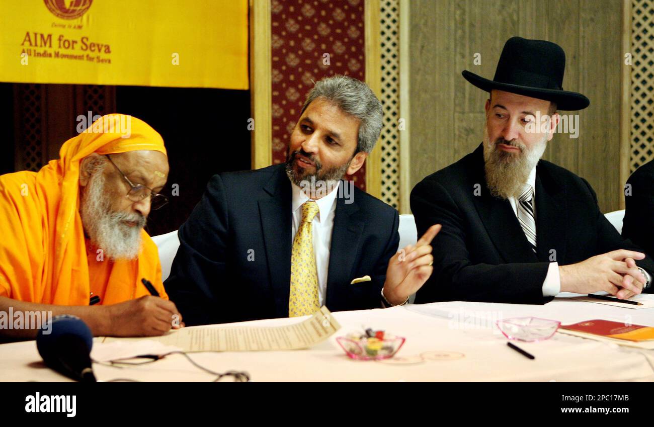 Hindu religious leader Swami Dayanand Saraswati, left, signs a protocol ...