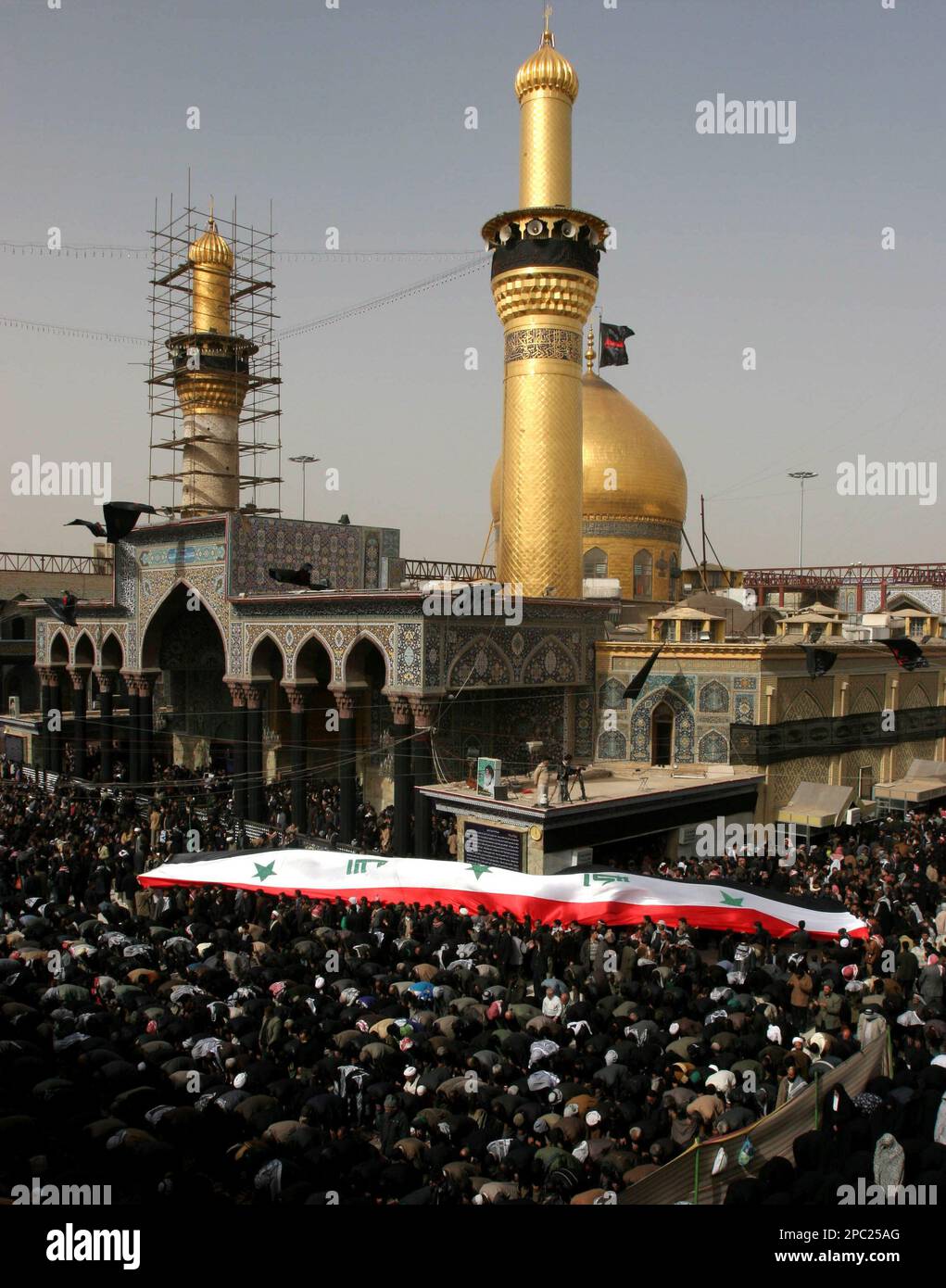 Iraqi pilgrims bring a huge national flag inside the shrine of Imam ...