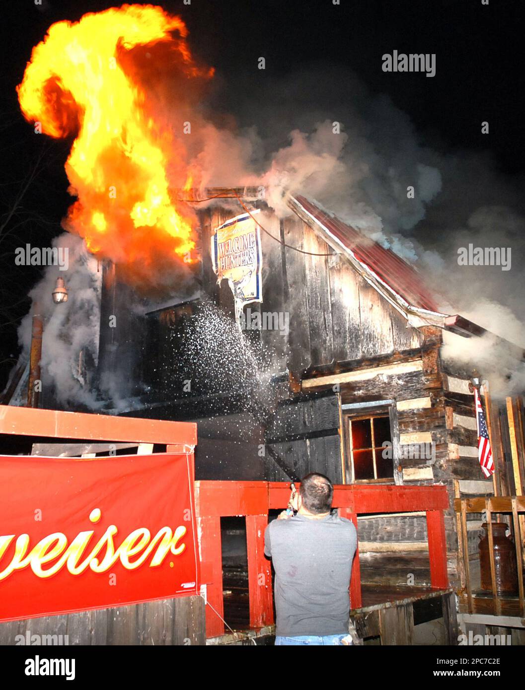 Dover volunteer firefighter Jackie Wheeler sprays water at an 1879 log ...