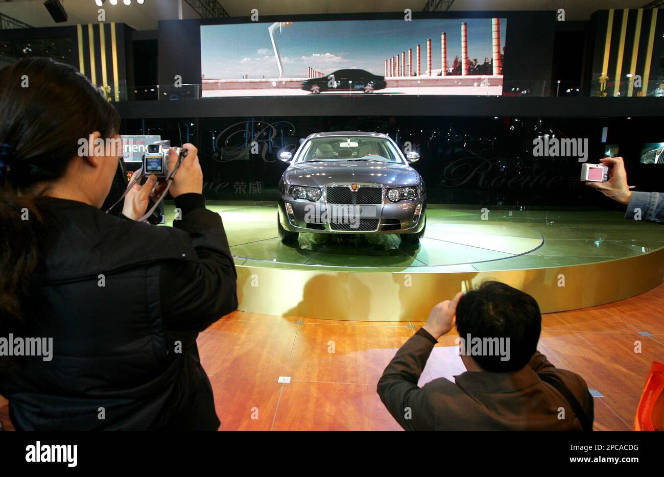Visitors take photos of the Roewe 750, made by Chinese auto maker SAIC ...