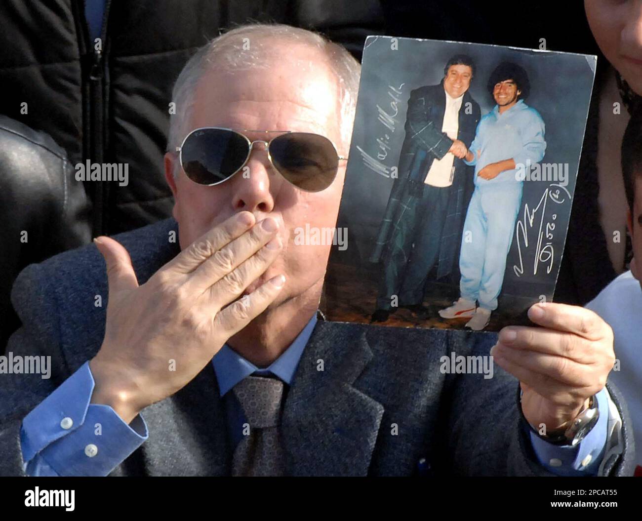 A man blows a kiss as he holds a picture showing singer Mario Merola ...
