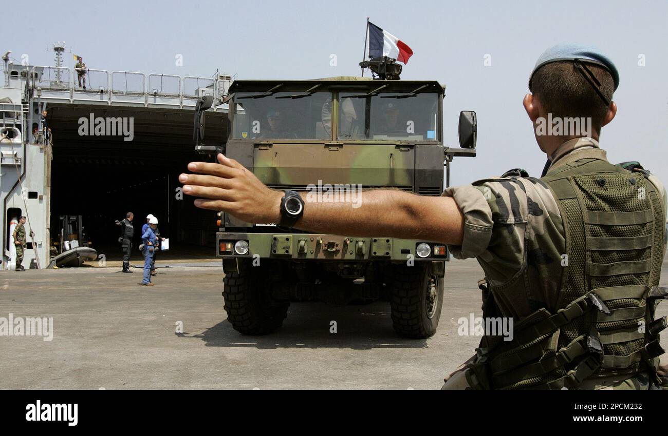 A United Nations peacekeeper from France directs a truck as it ...