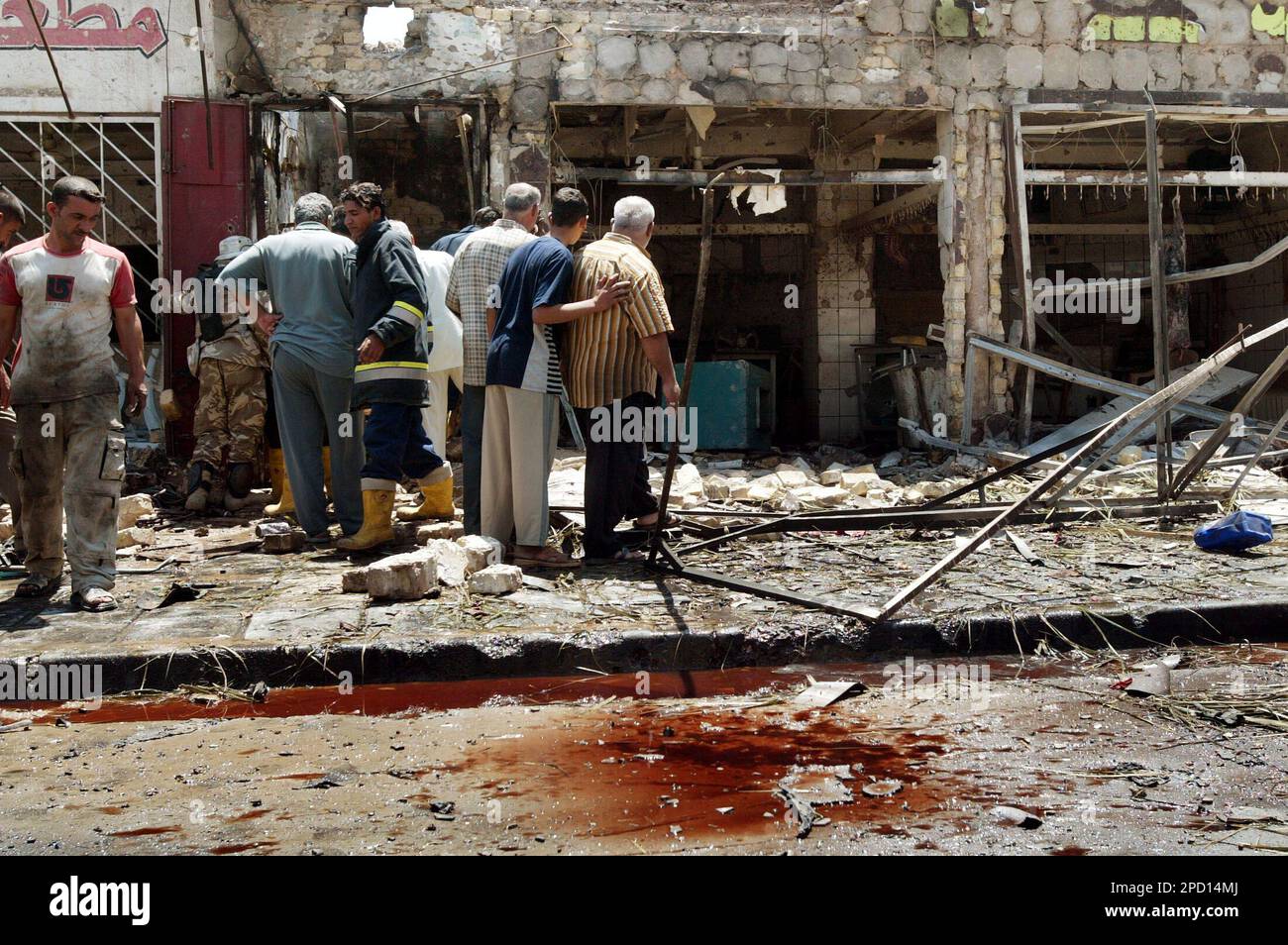 Iraqi police and firemen attend the scene outside a butcher's shop ...
