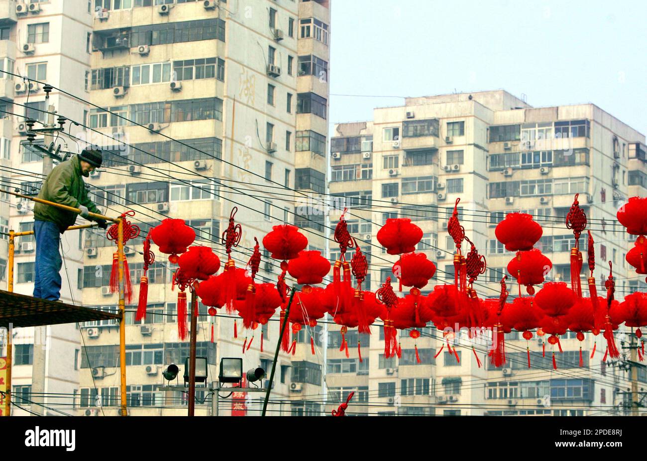 A Chinese worker puts up red lanterns as part of the traditional ...