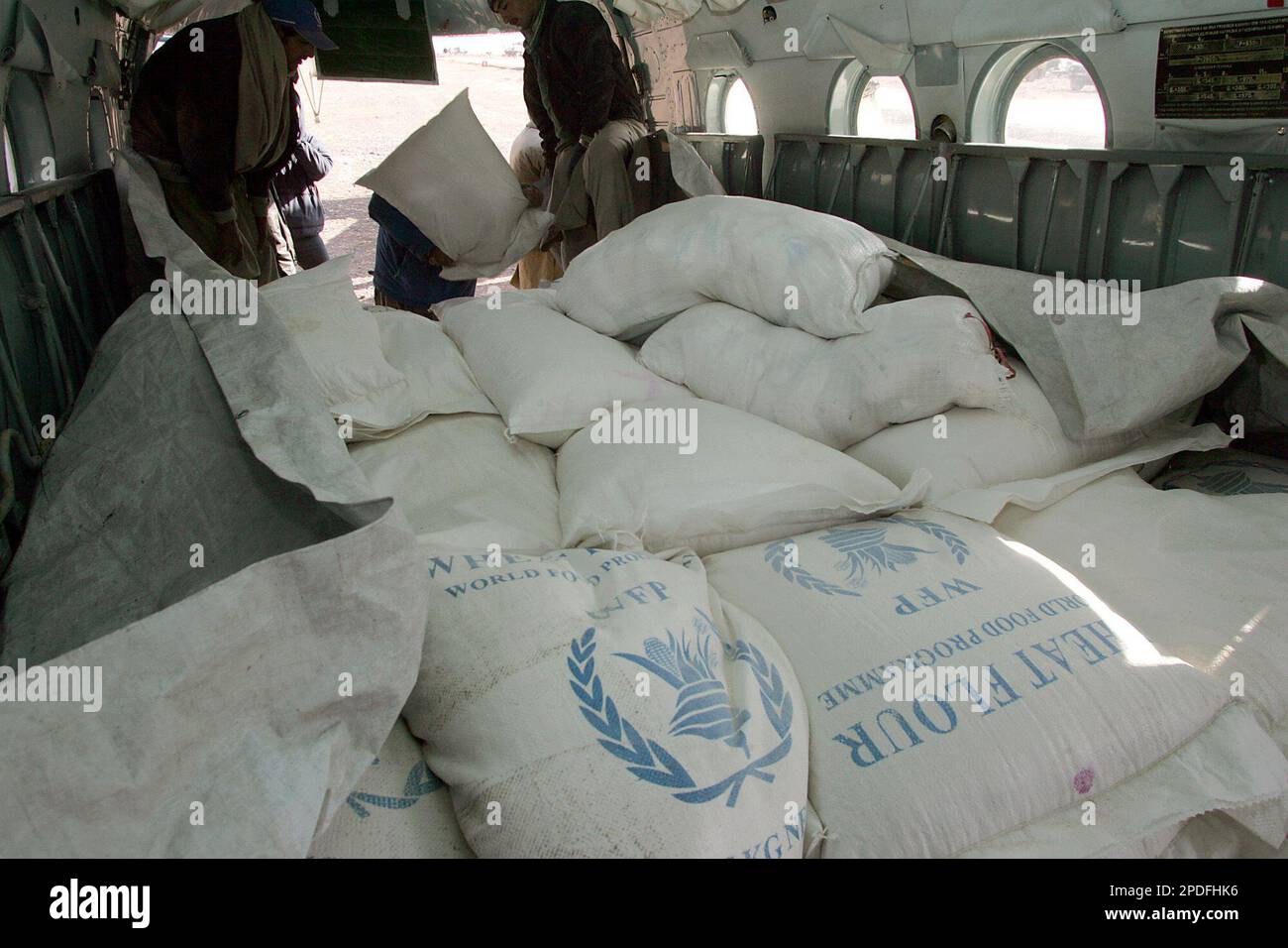 Laborers of World Food Program load the relief aid into a UN helicopter ...