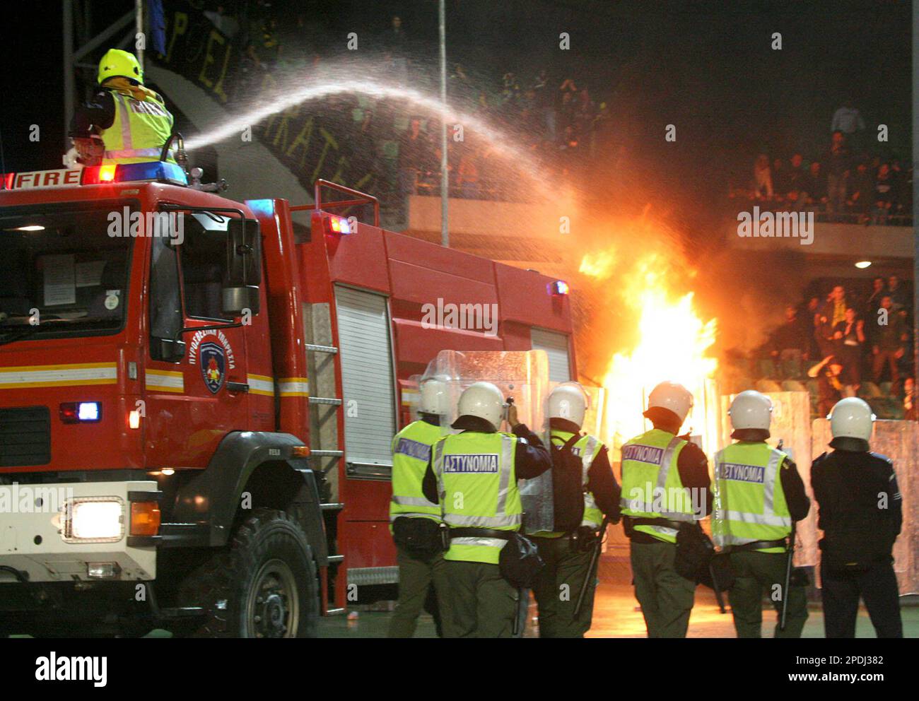 A Greek Cypriot fire fighter, directs water onto a fire on the stands ...
