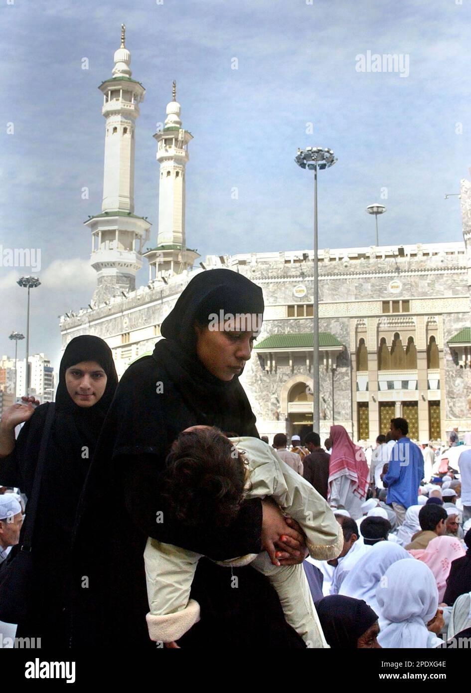 ** FILE ** A Muslim pilgrim carries her son around the great mosque to ...