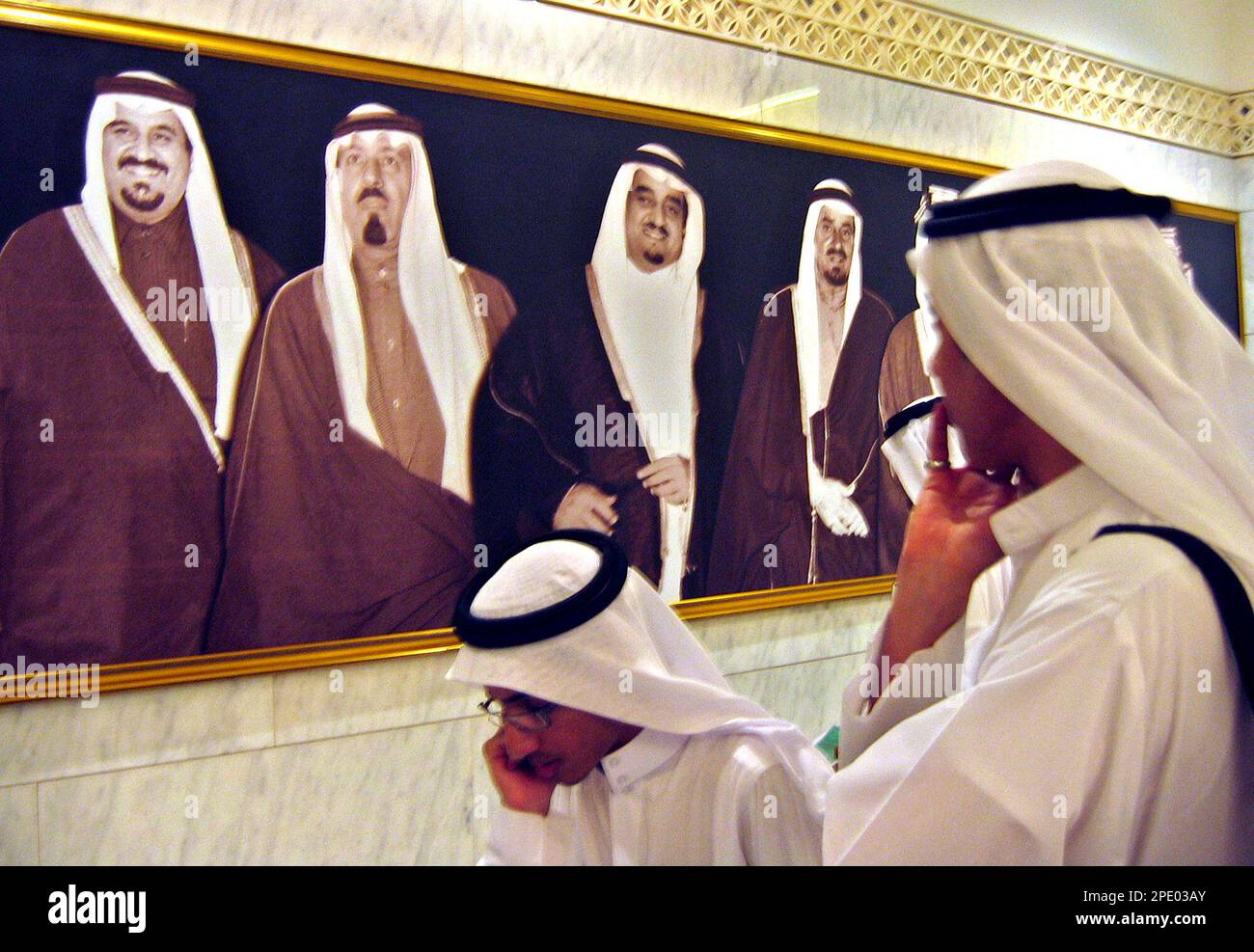 Saudi journalists stand next to the portrait of the Saudi royal family ...