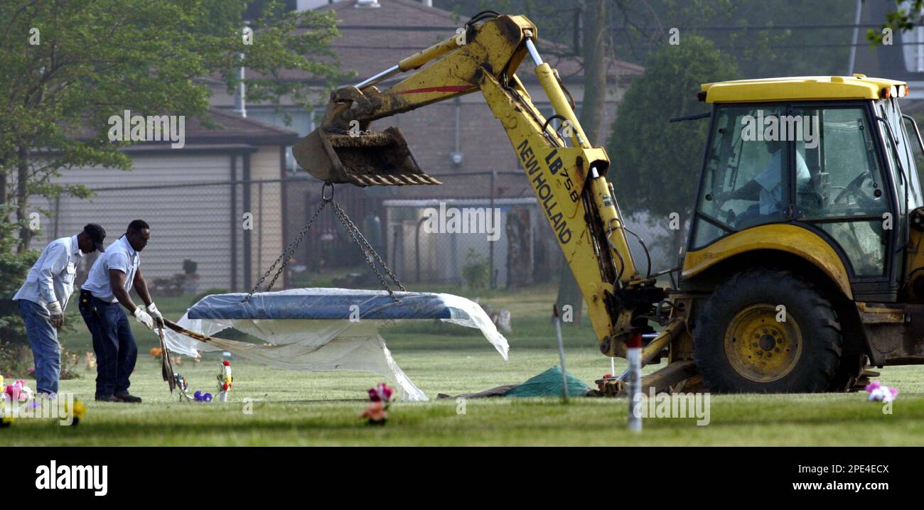 Burr Oak Cemetery workers remove plastic from around the new vault ...