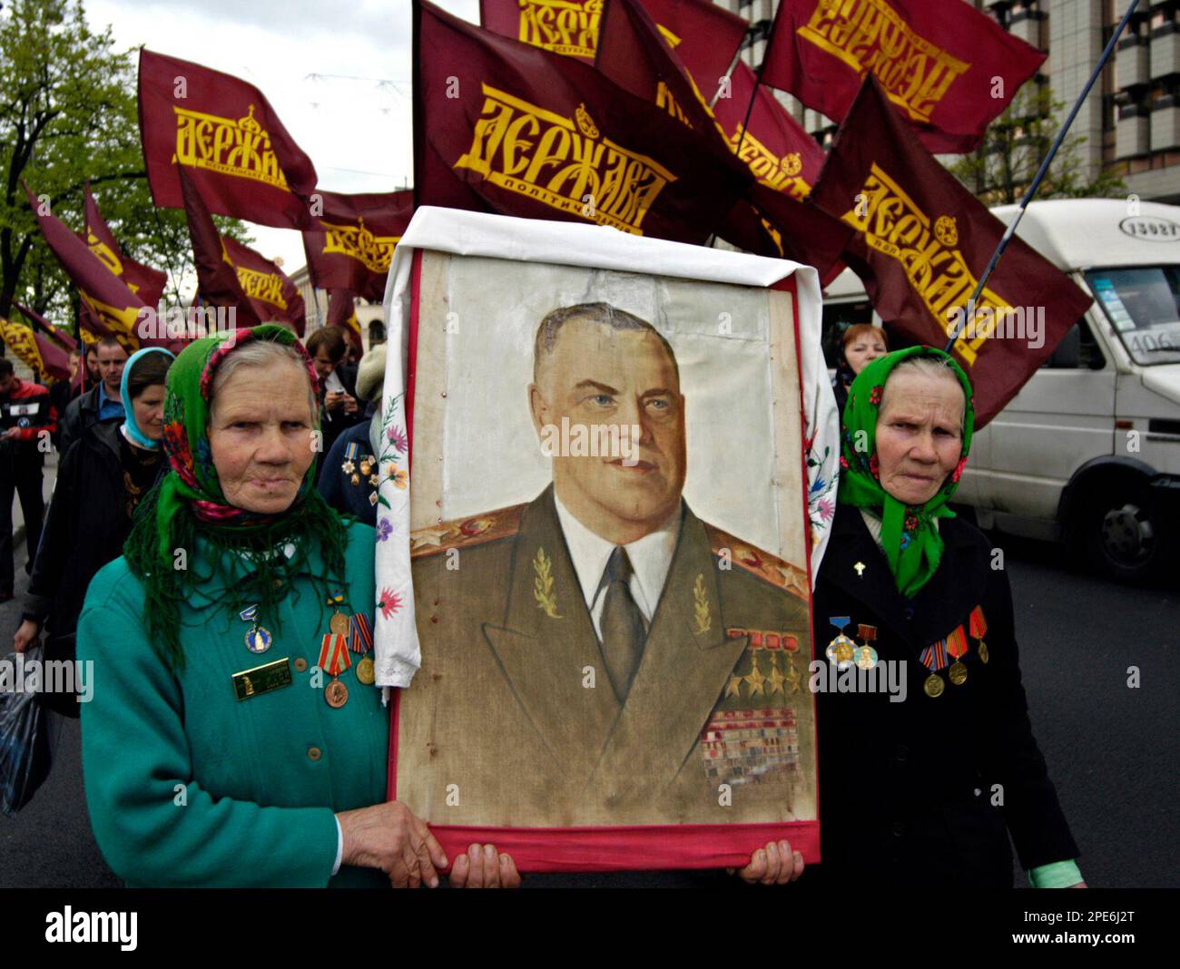Two elderly sisters Galina, left, and Maria Shchura carry a portrait of ...
