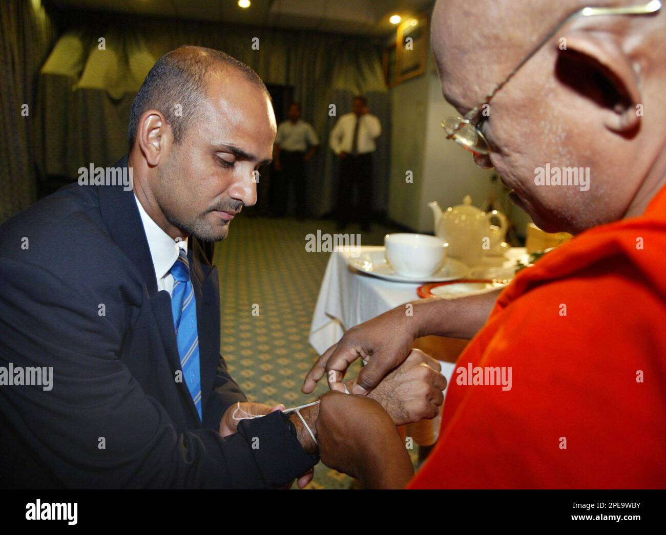 A Buddhist monk ties a blessed thread on the wrist of Sri Lankan ...