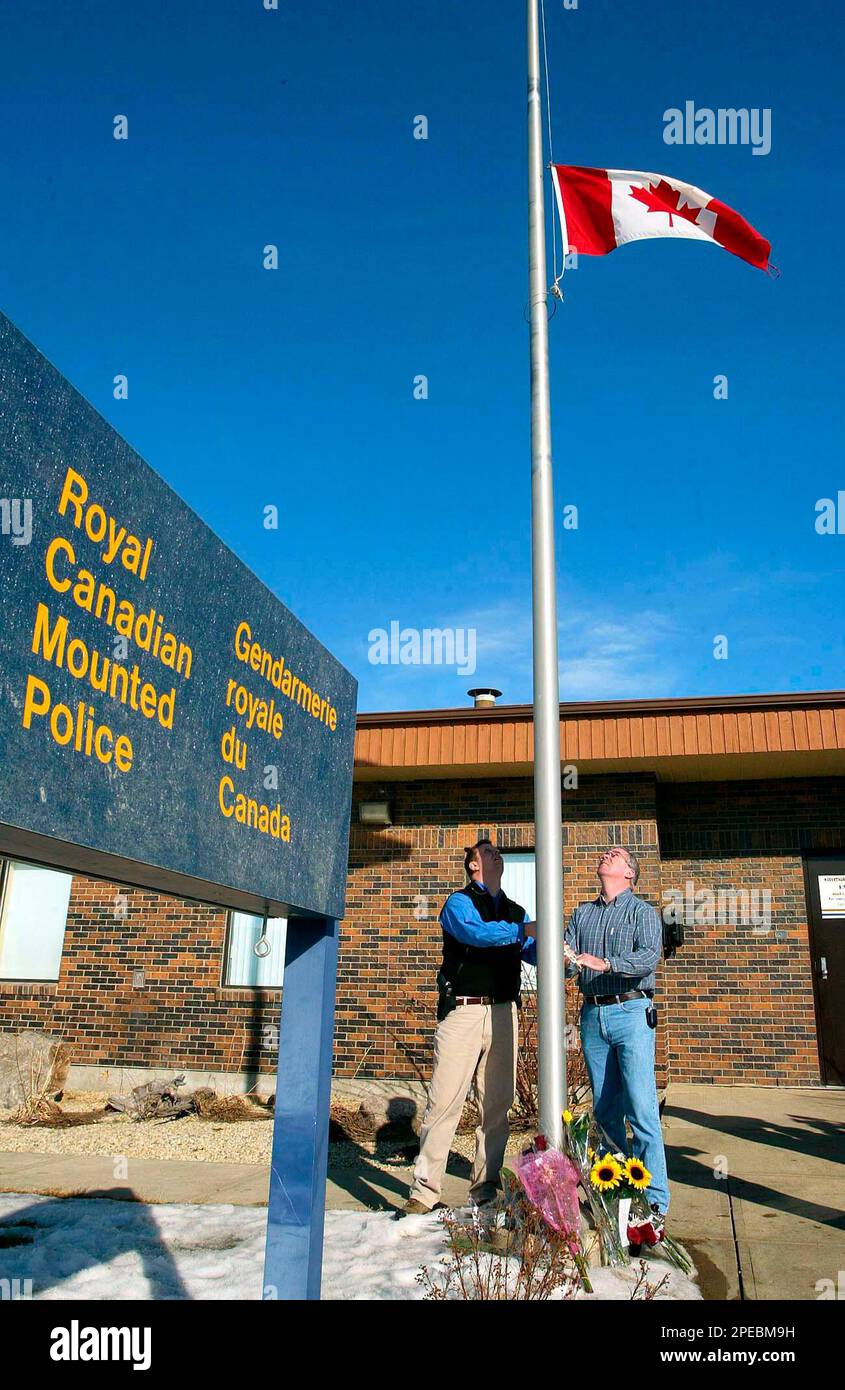 Members of the Royal Canadian Mounted Police (RCMP) lower the flag at ...