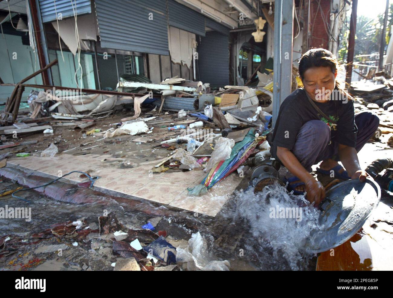 A Thai shopkeeper cleans what is left of her resturant on Tuesday, Jan ...