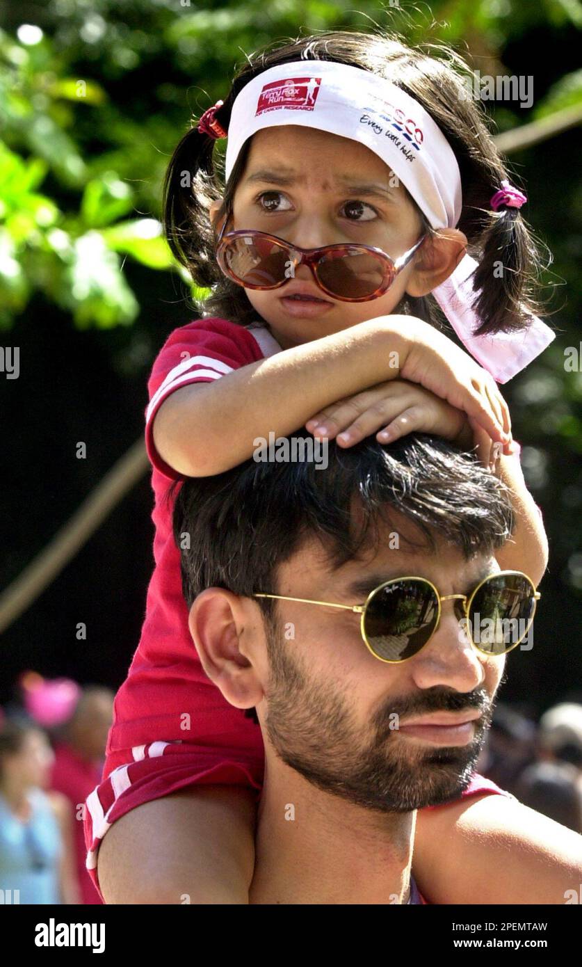 Manoj Dighe carries his daughter Tanisha on his shoulders as they wait ...