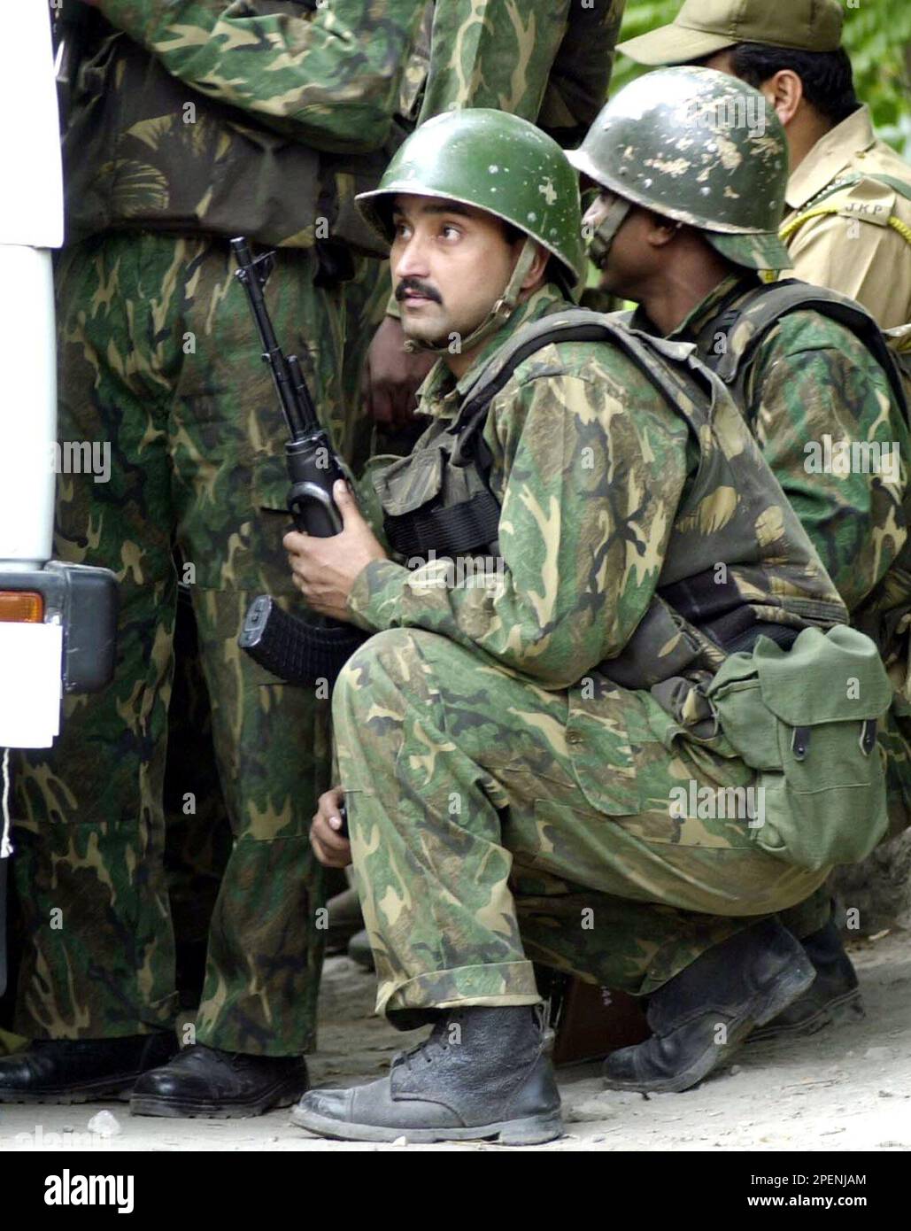 Indian paramilitary soldiers take cover behind an armored vehicle ...